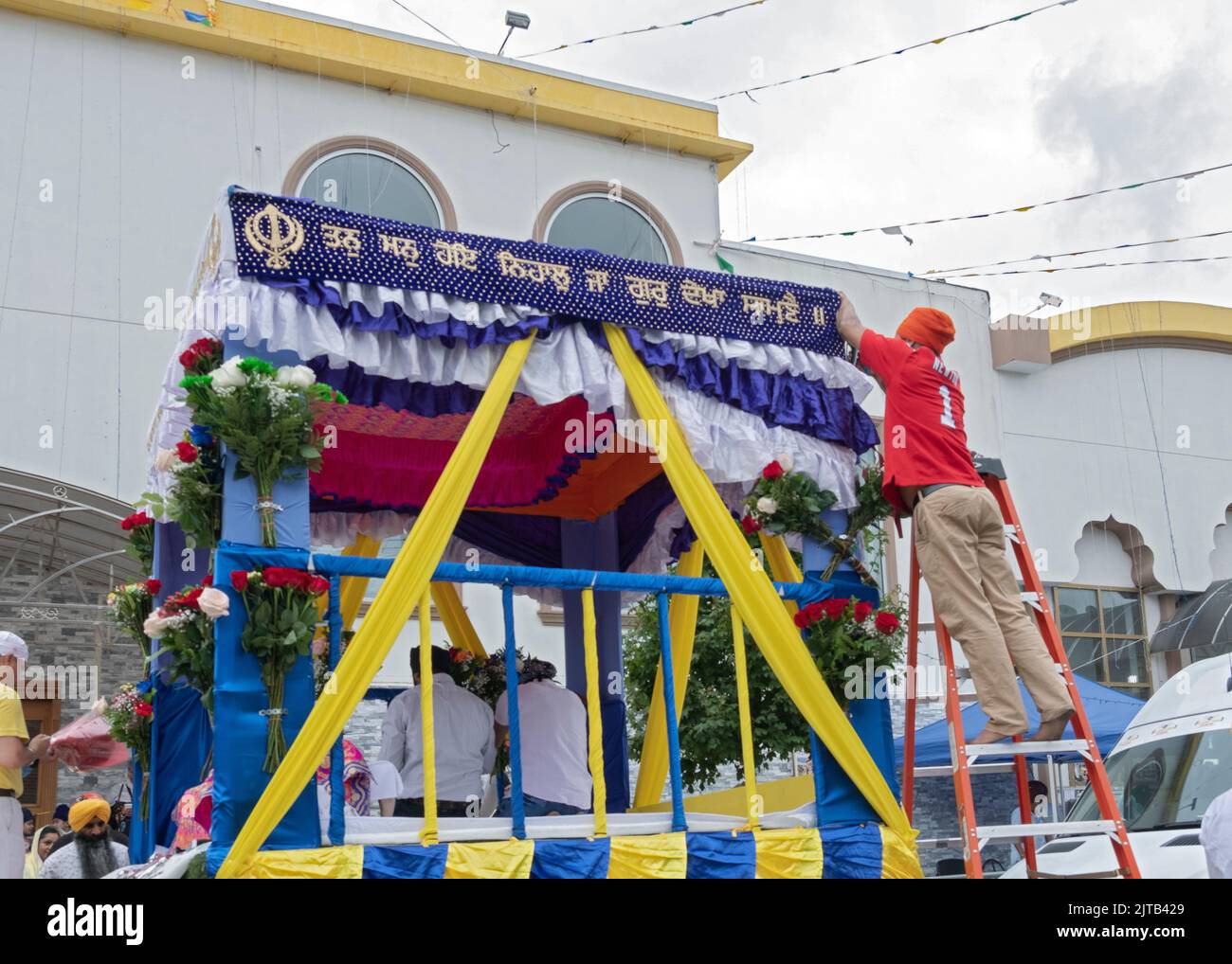 A Sikh man puts bunting on the mani float of the 2022 Nagar Kirtan ...