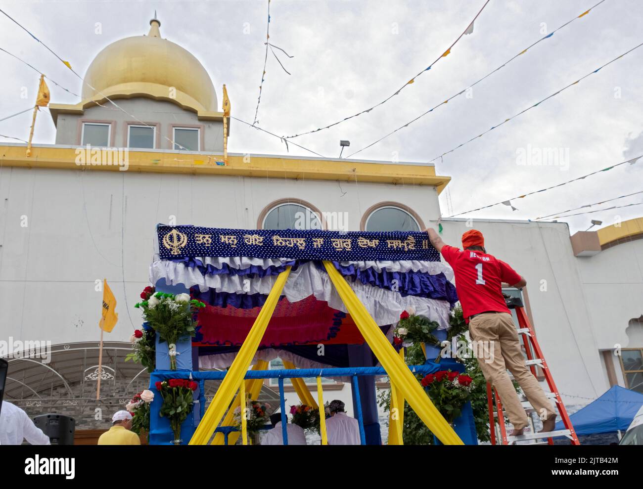 A Sikh man puts bunting on the mani float of the 2022 Nagar Kirtan ...