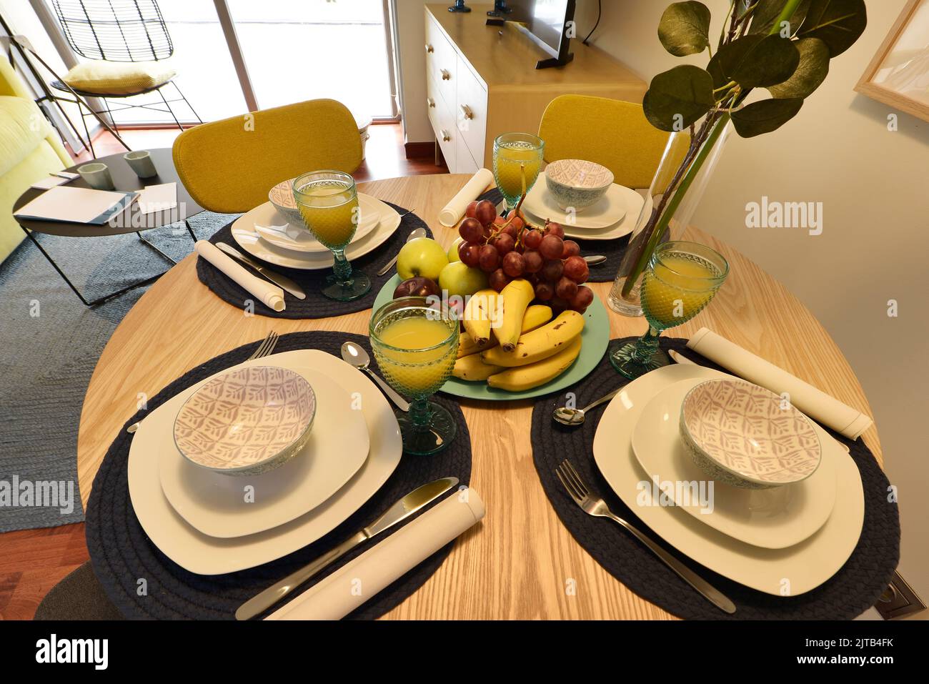 Circular wooden dining table with breakfast service with assorted fresh ...