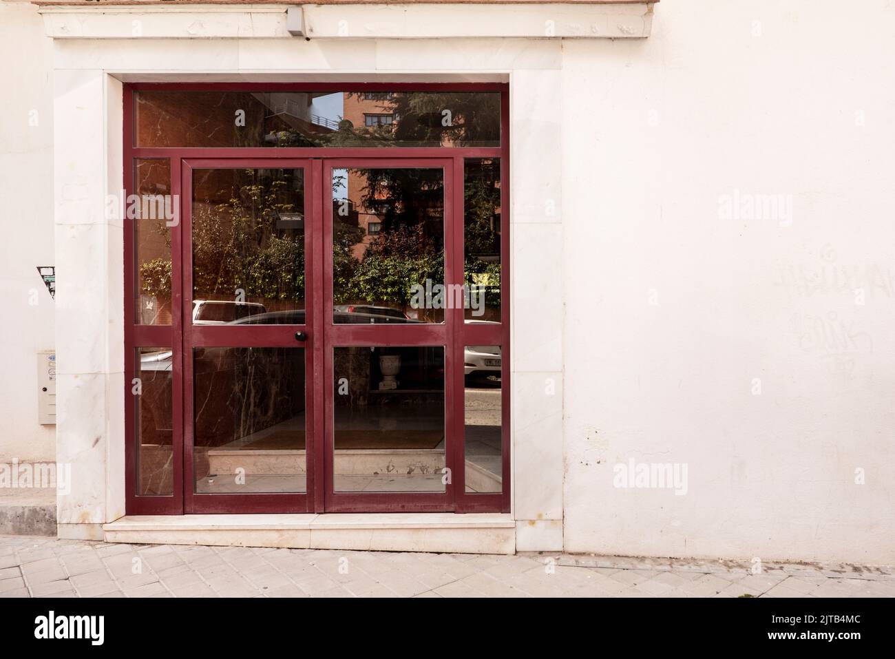 Portal of a house with red metal and glass doors on a white facade ...