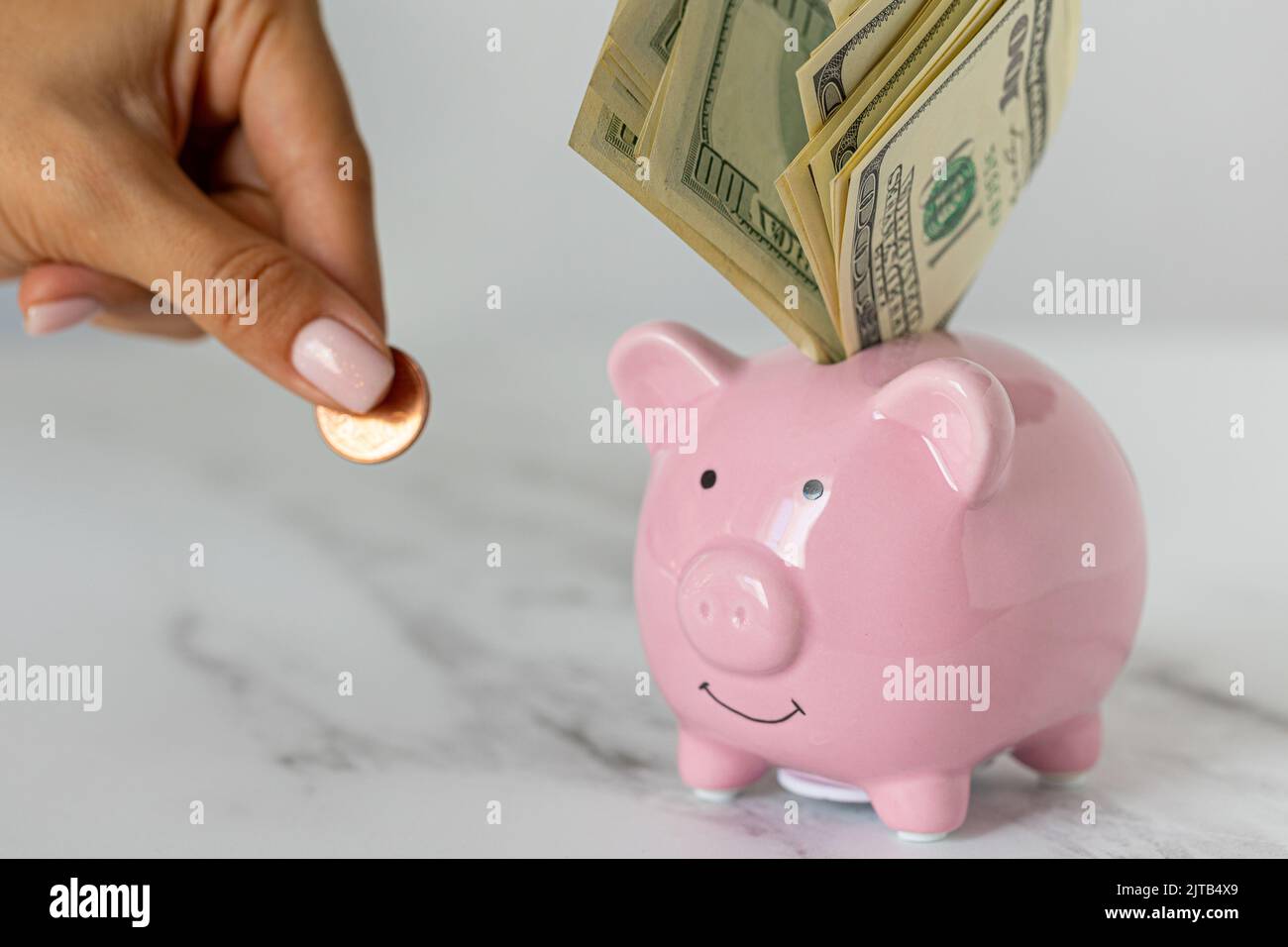 Close-up of a piggy bank with dollars and a woman's hand holding out ...