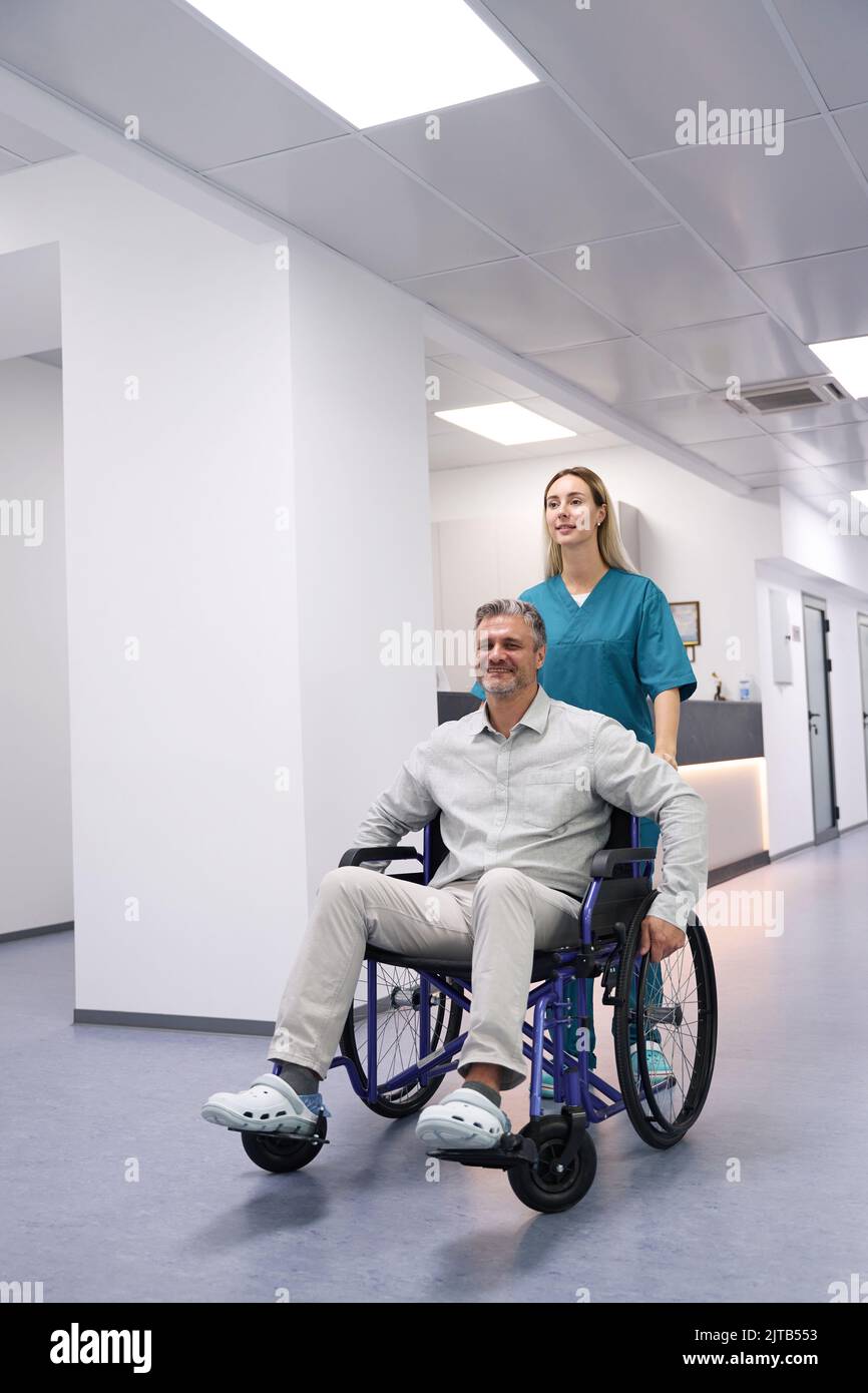 Doctor in a blue suit carries a patient along the corridor Stock Photo ...