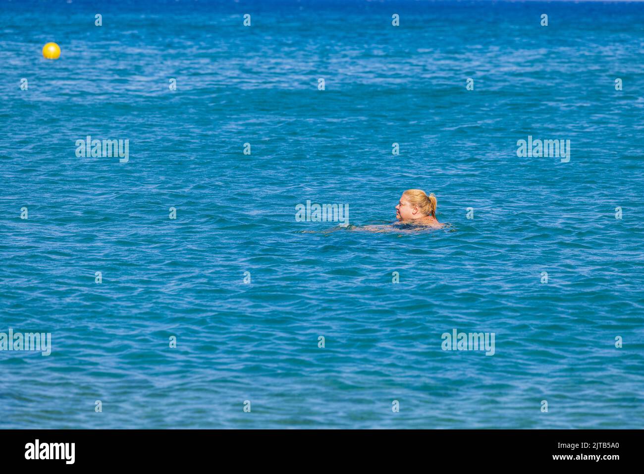 Close up view of woman on surface of blue water floating in sea. Greece ...