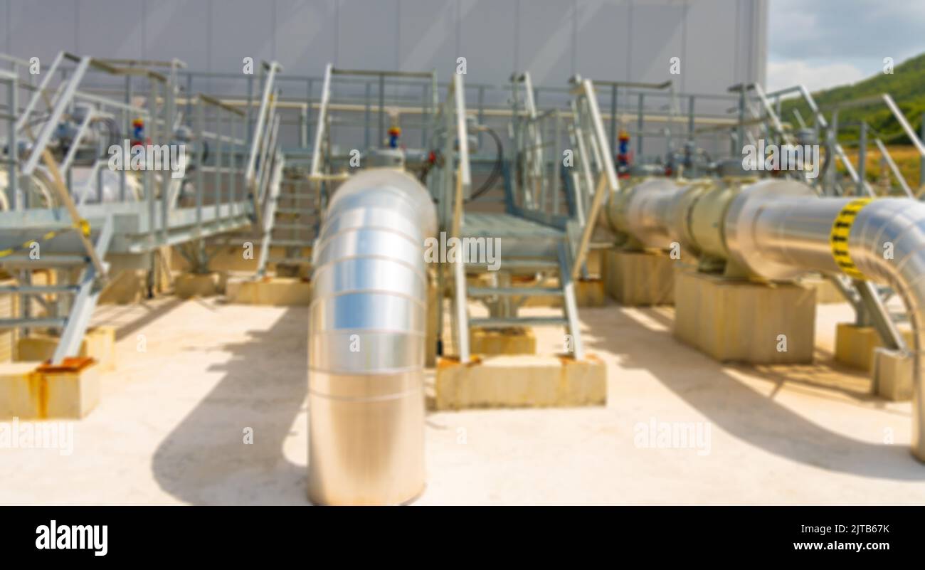 Blurred a row of pipes carrying natural gas with cranes and other ...