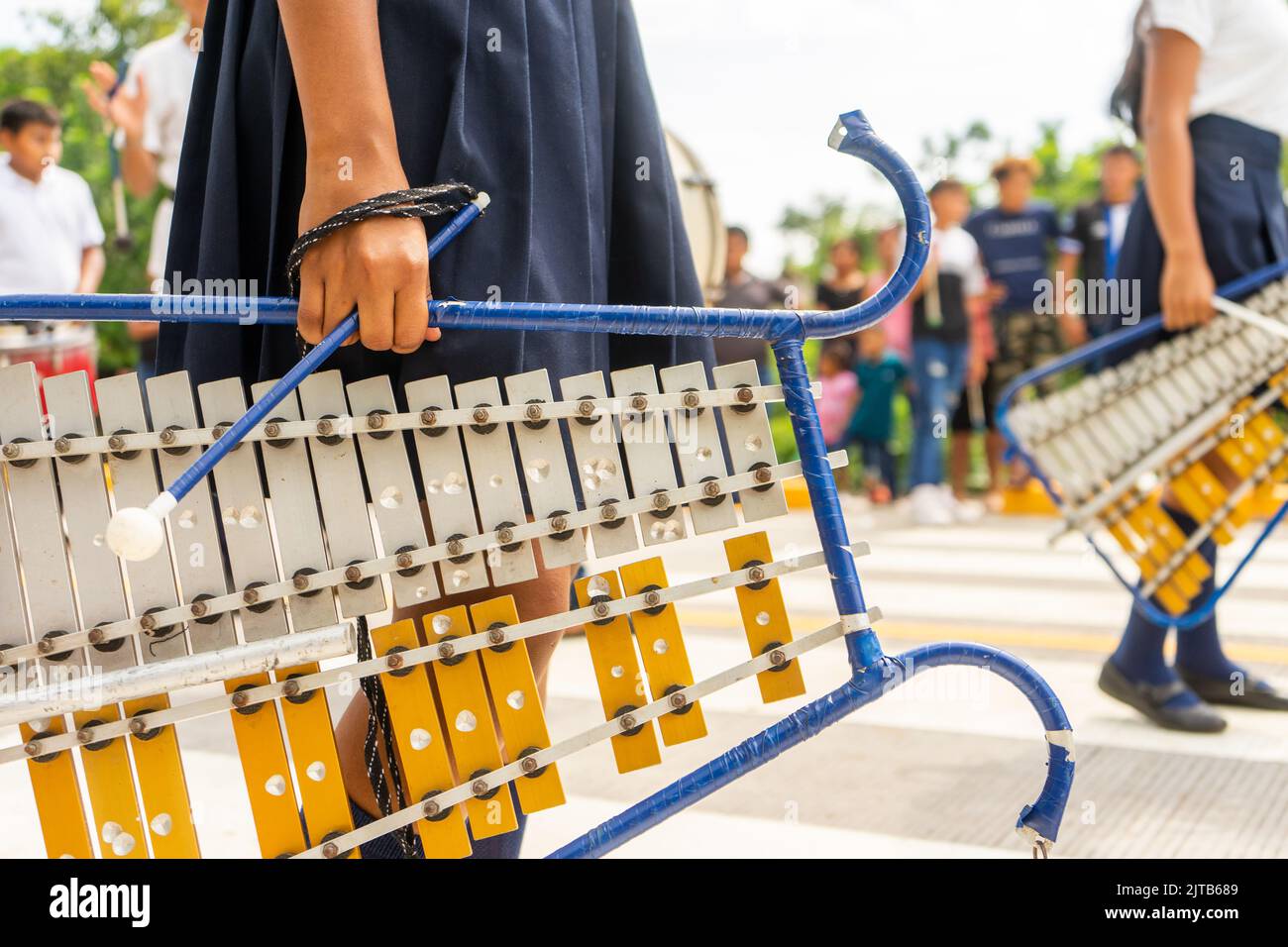 Latin American student girls with uniforms carrying musical instruments ...