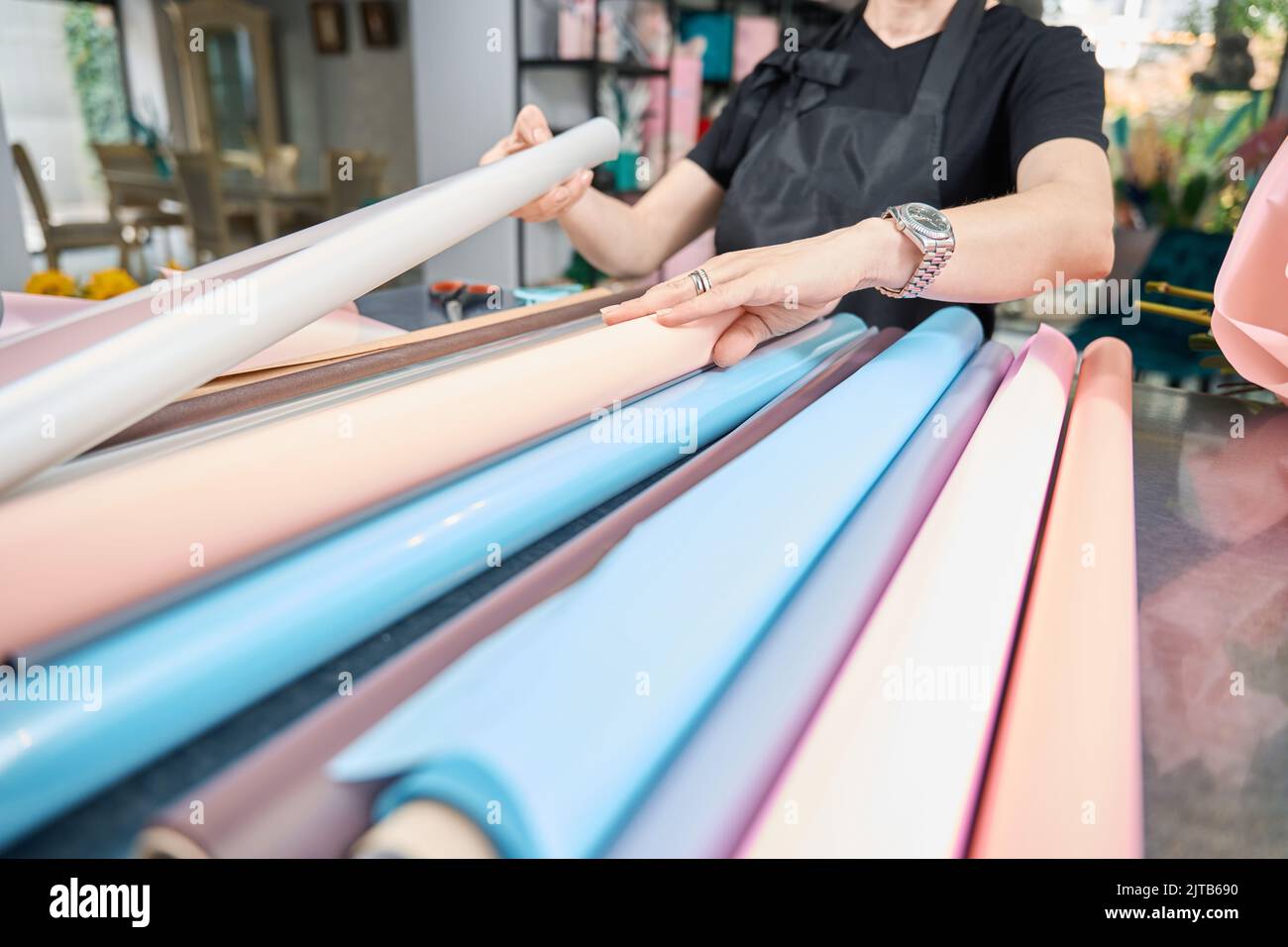 Woman florist chooses paper for bouquet in flower boutique Stock Photo ...