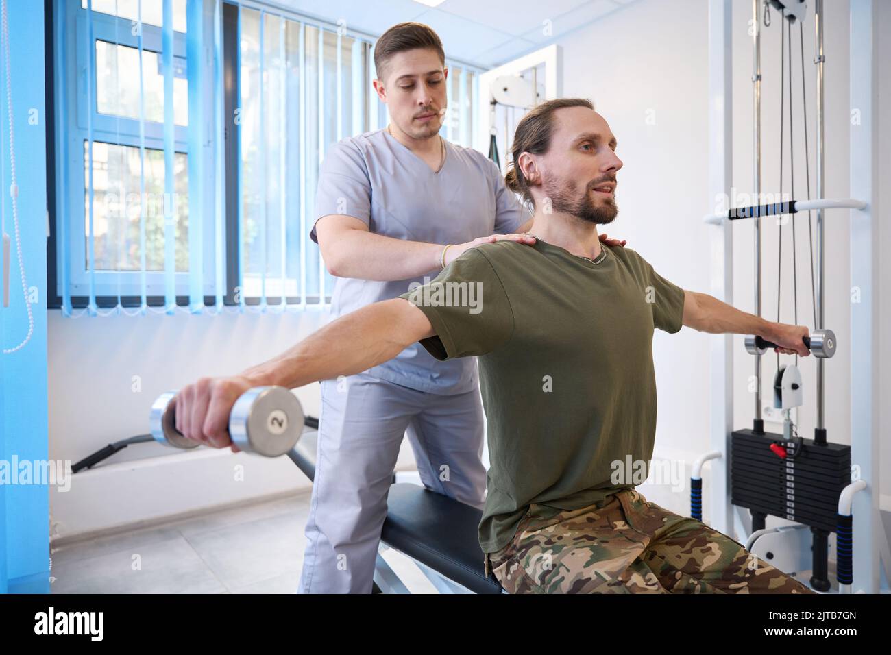 Patient doing special exercises with dumbbells under supervision of ...
