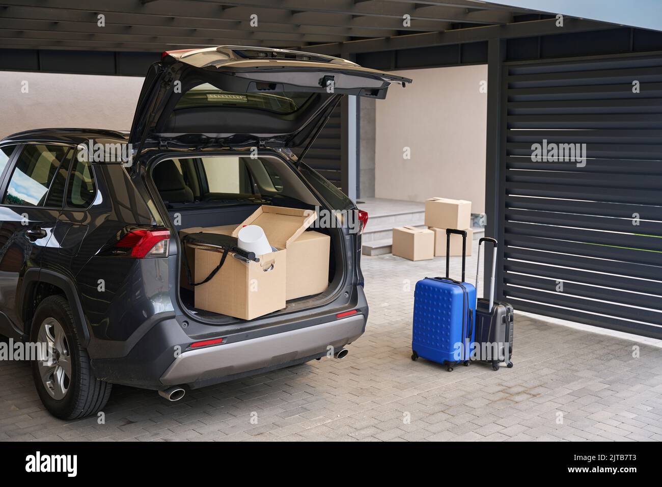 Black car in yard with open trunk and boxes for moving Stock Photo - Alamy