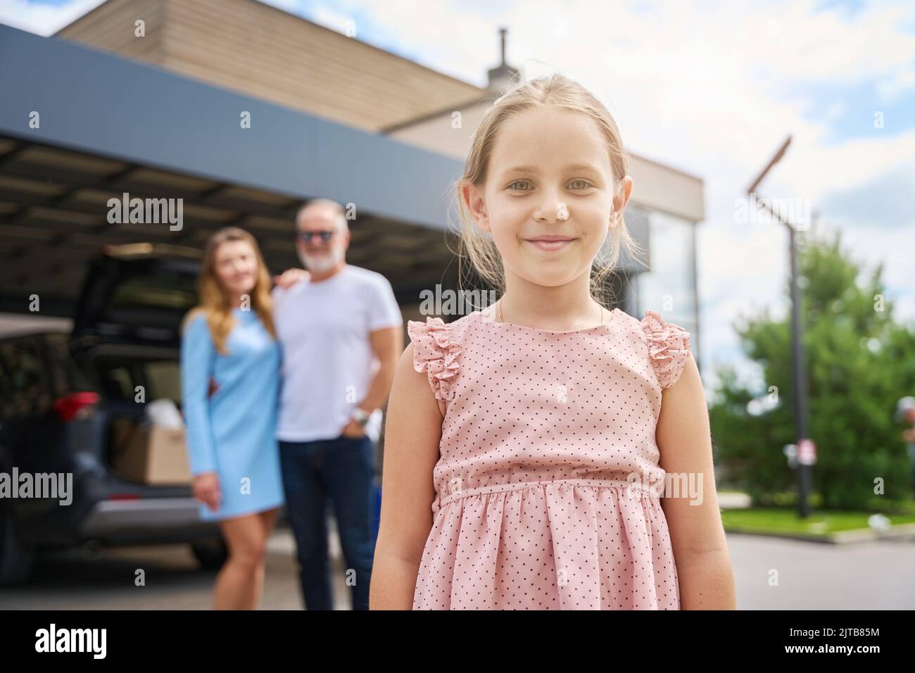 Girl in front of new house, parents are standing behind Stock Photo - Alamy