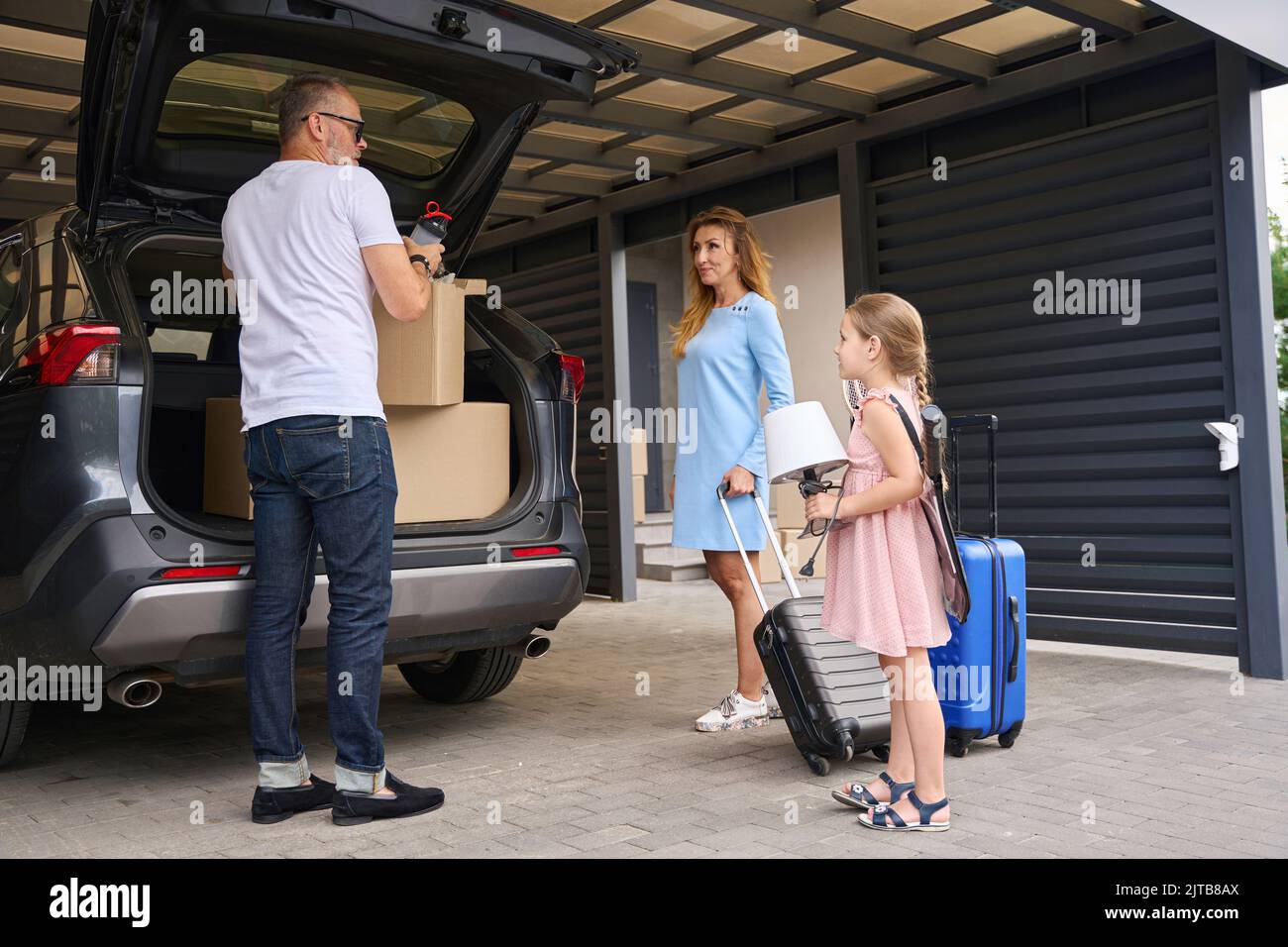 Family takes out things and boxes for moving from car Stock Photo - Alamy
