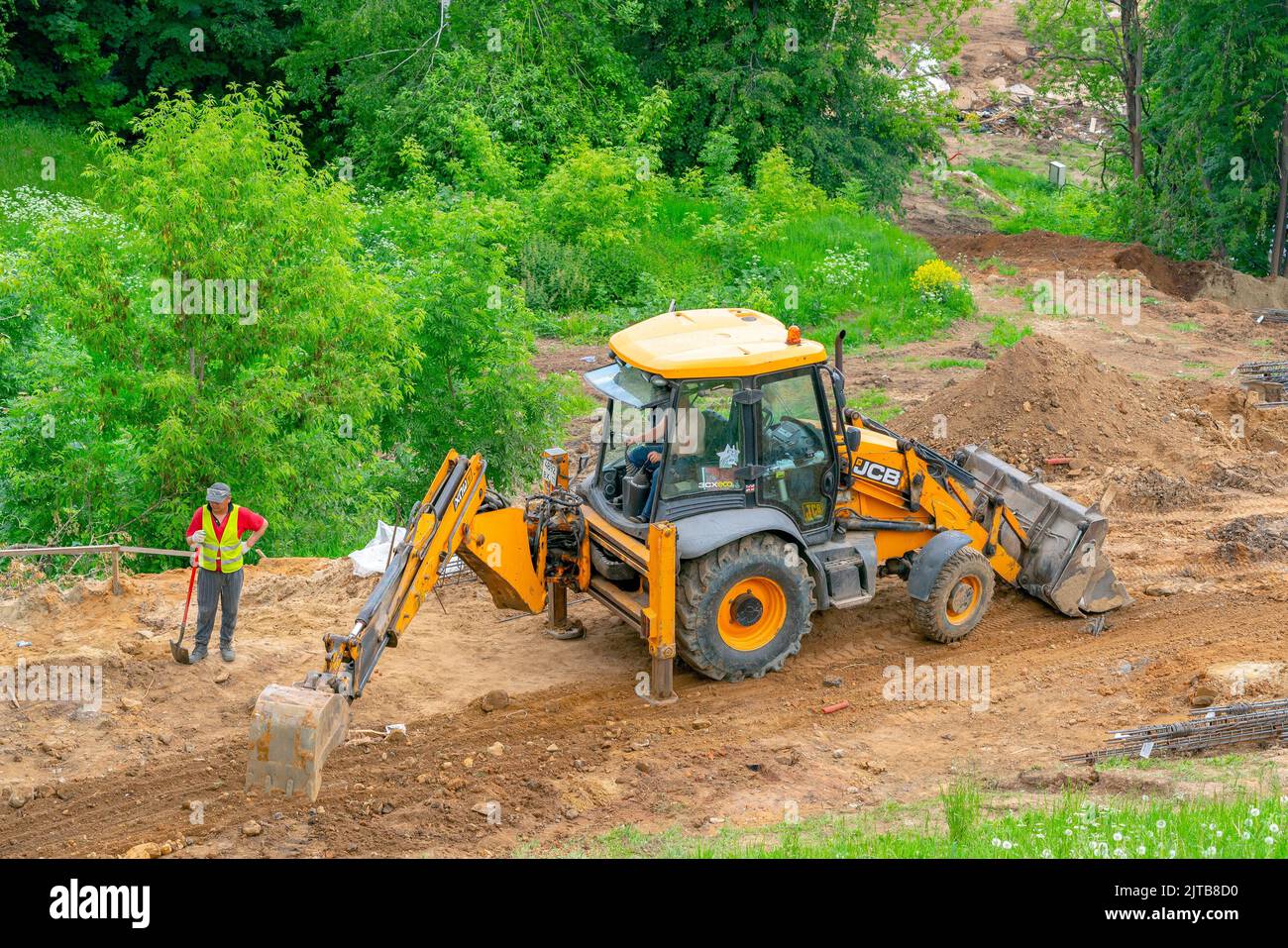 The excavator digs the ground on the road Stock Photo - Alamy
