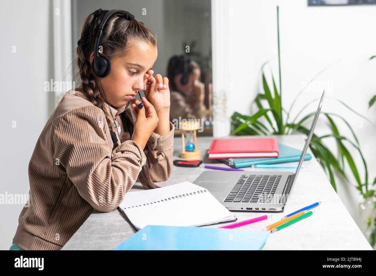 Tired schooler child girl at home with laptop for remote connection ...