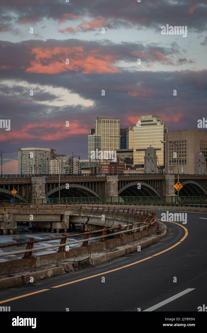A vertical shot of a curvy road against the city buildings and sky at ...