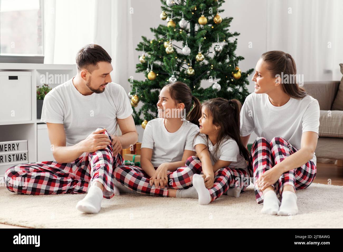 happy family sitting under christmas tree at home Stock Photo - Alamy