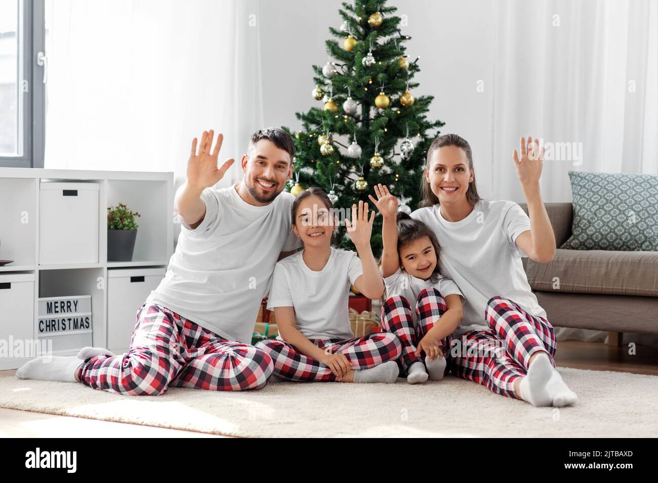 happy family sitting under christmas tree at home Stock Photo - Alamy