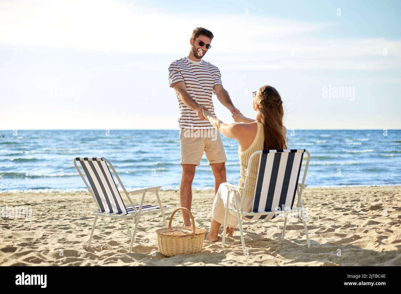 happy couple sitting in folding chairs on beach Stock Photo - Alamy