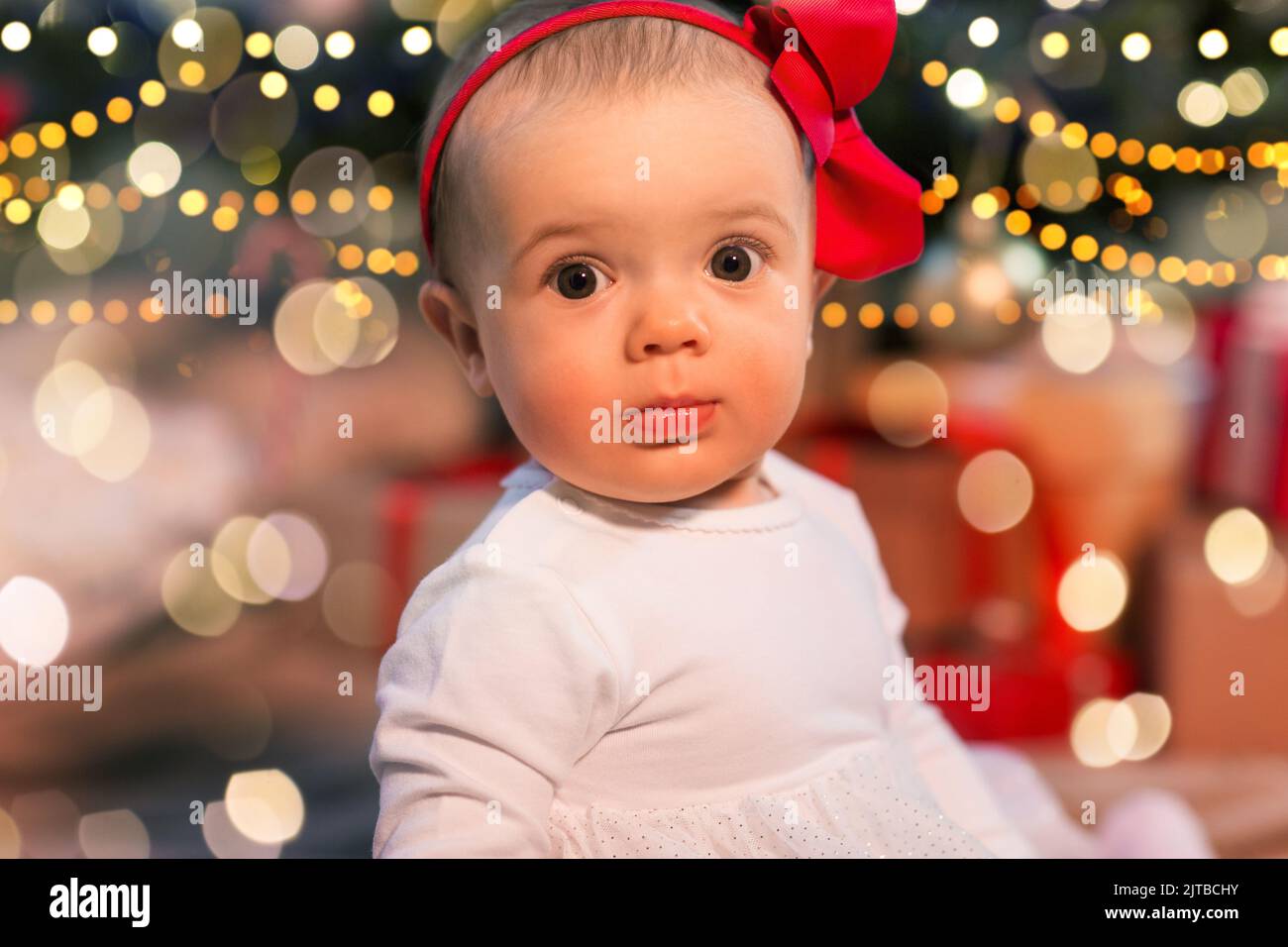beautiful baby girl over christmas tree lights Stock Photo - Alamy