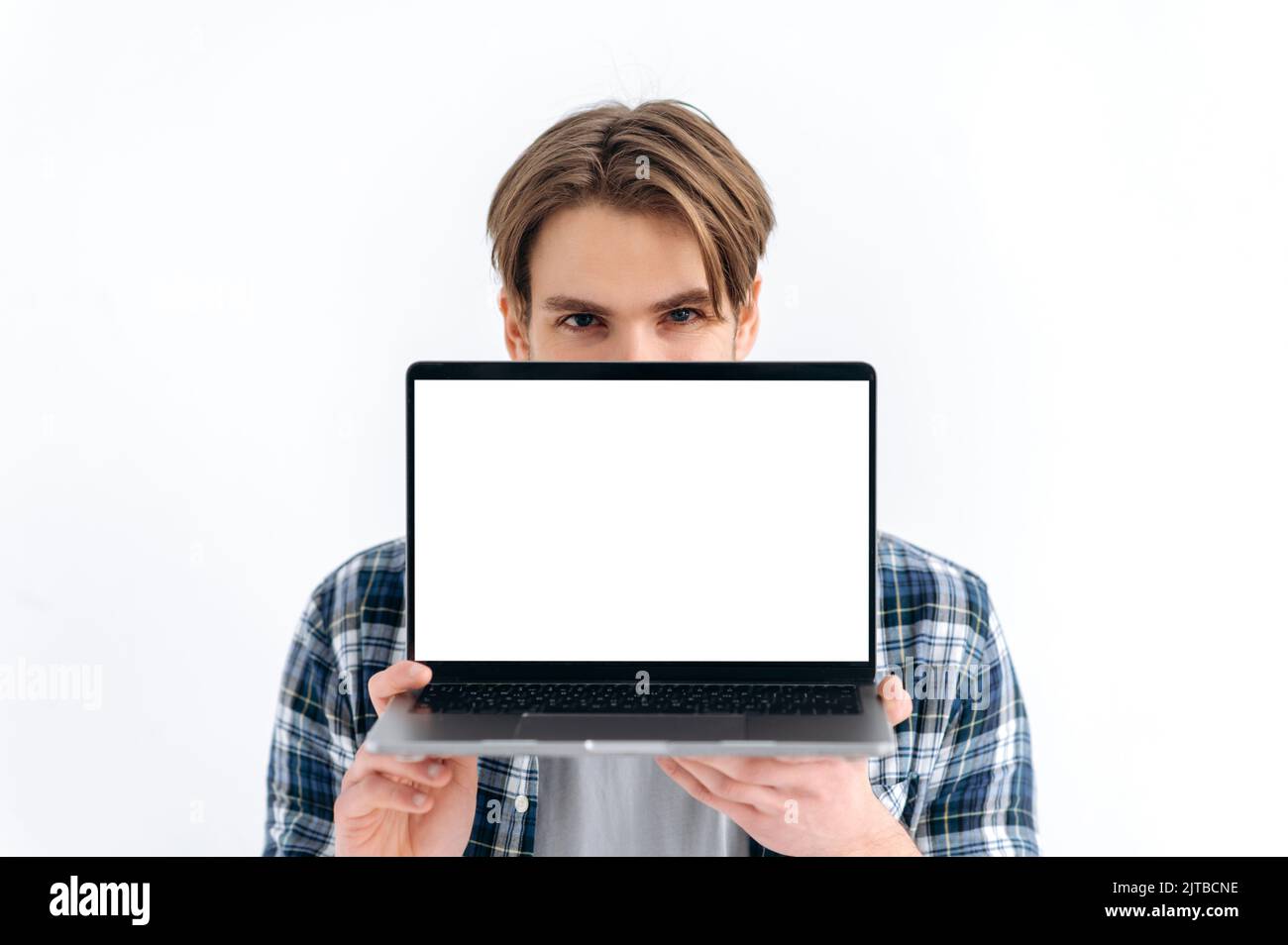 Amazed excited caucasian young man peeking out from behind laptop ...