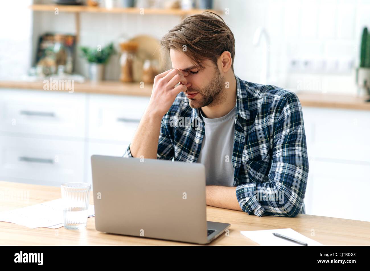Frustrated sad caucasian man, closed eyes, massages his bridge nose ...