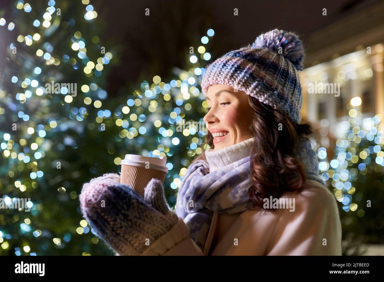 happy woman drinking coffee over christmas lights Stock Photo - Alamy