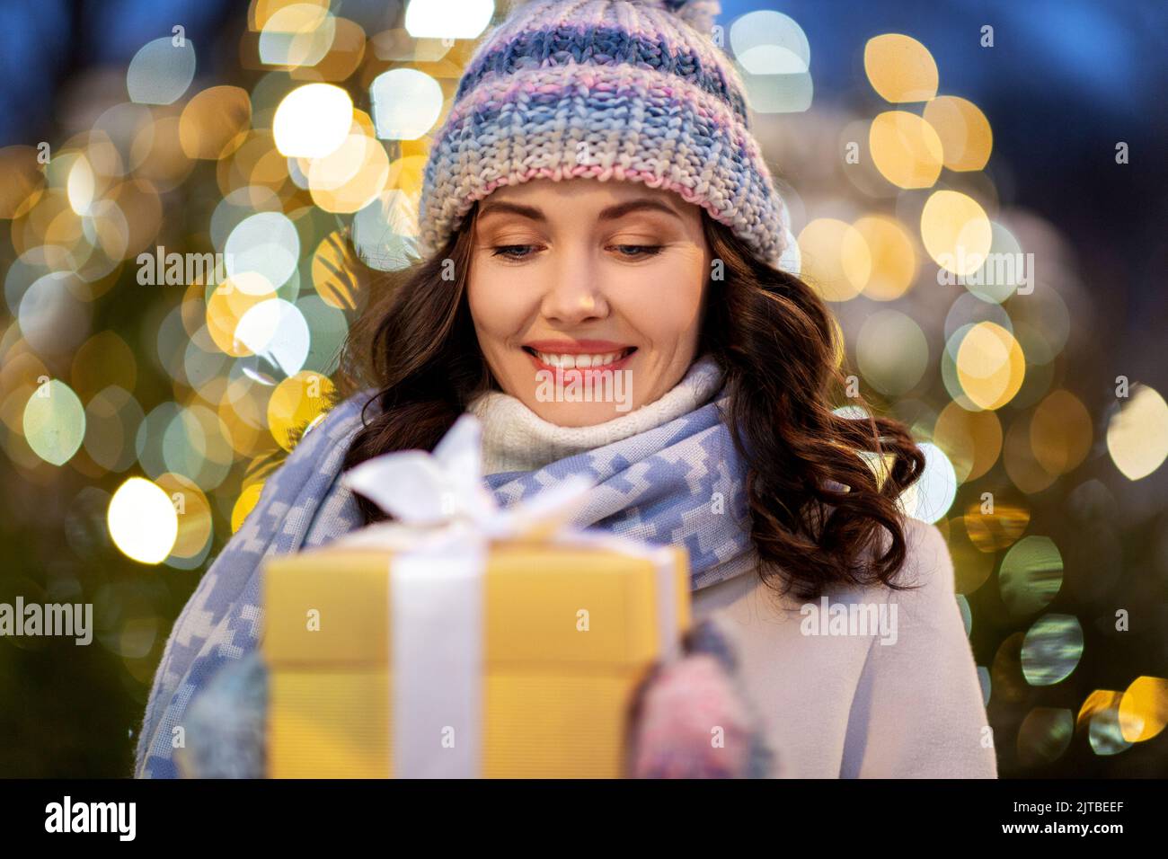 happy woman with christmas gift over lights Stock Photo - Alamy