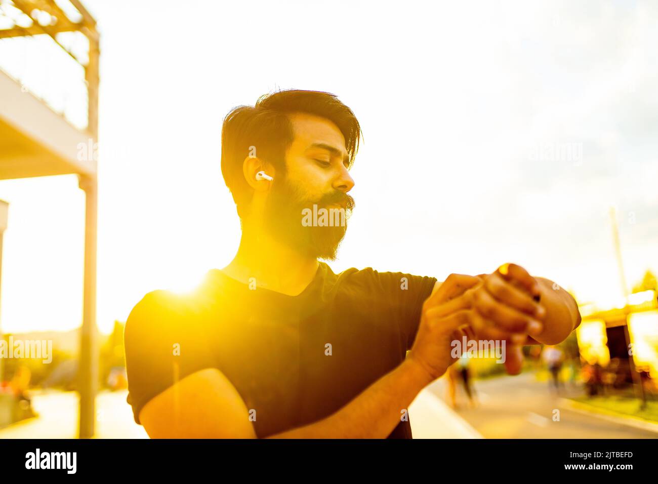 indian man in black t-shirt check time outdoors in sunset gold lights ...