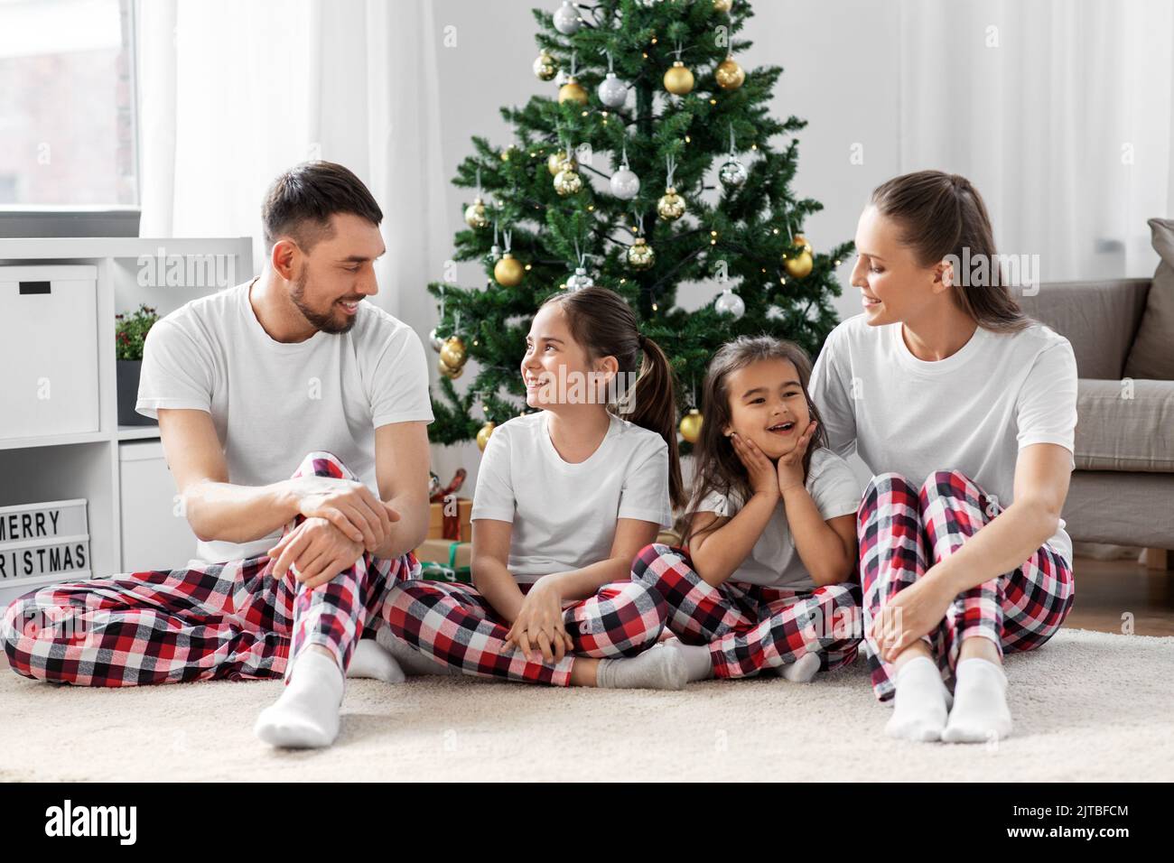 happy family sitting under christmas tree at home Stock Photo - Alamy