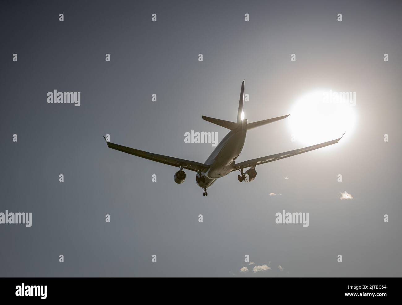 A plane flying under the sunshine before landing Stock Photo - Alamy