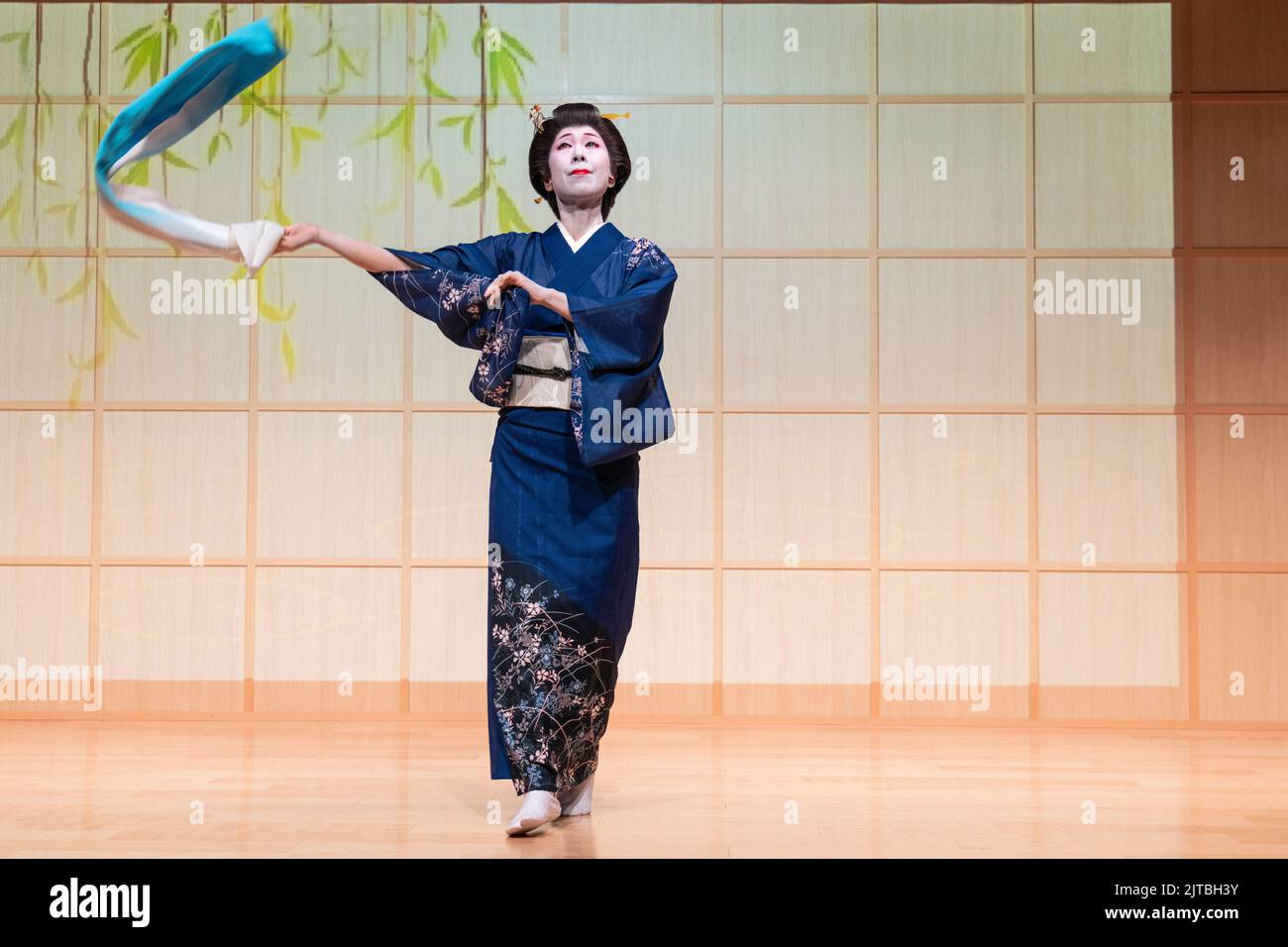 A Japanese geisha wearing a kimono, performs a traditional dance called ...