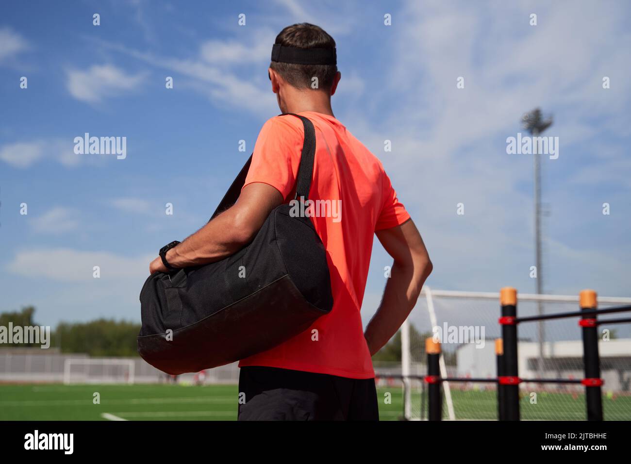 Back view of sportsman with bag standing at the open stadium. Sport ...