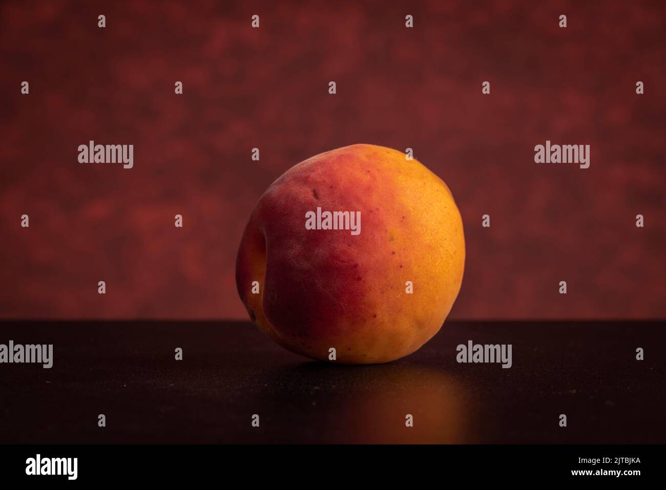 Fresh color apricots on black table with red background Stock Photo - Alamy