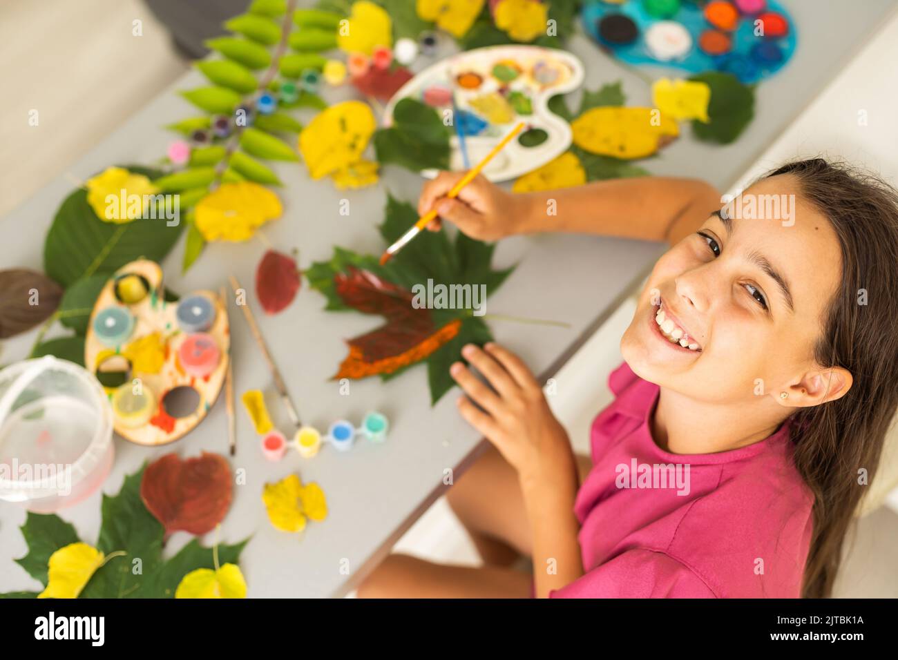 A child paints a picture of an autumn leaf with paints. Children's ...