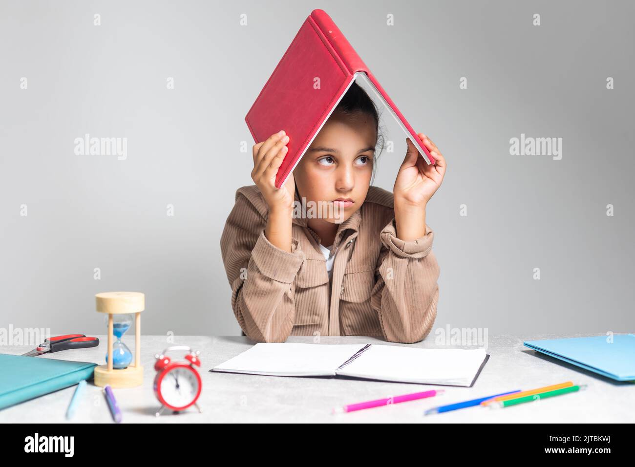 Pretty little girl tired of doing homework at table Stock Photo - Alamy
