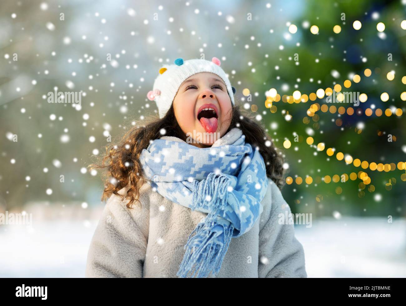 happy girl catching snow by her tongue in winter Stock Photo - Alamy