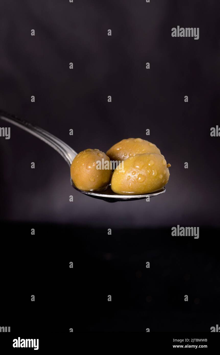 Calabrese Olives in a Spoon with Studio Lighted Background Vertical ...