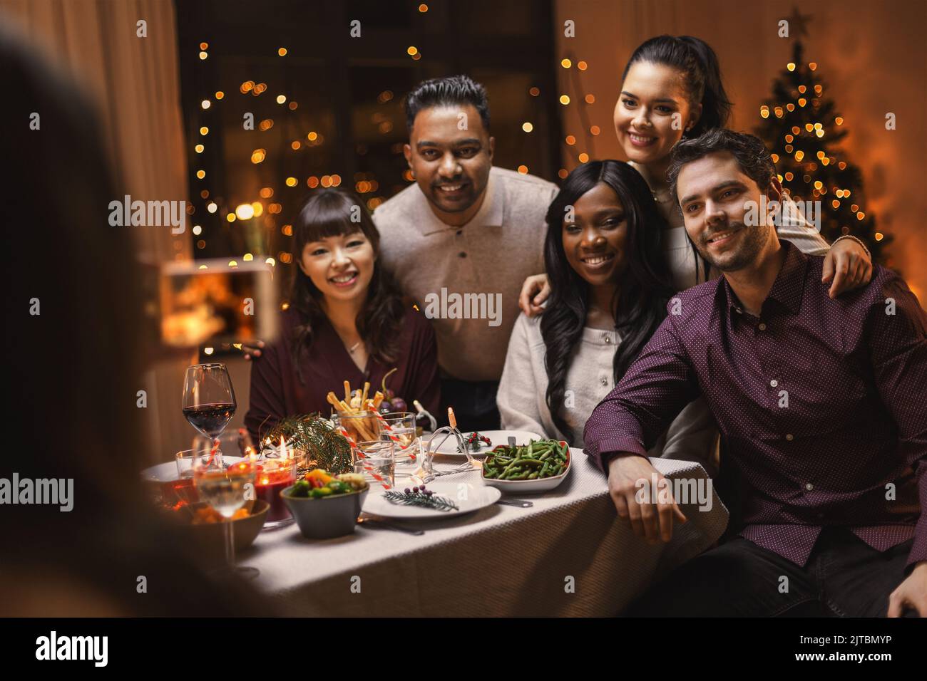 happy friends photographing at christmas dinner Stock Photo - Alamy
