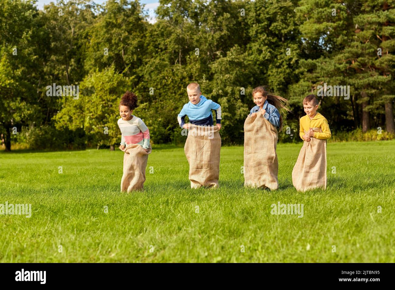 happy children playing bag jumping game at park Stock Photo - Alamy