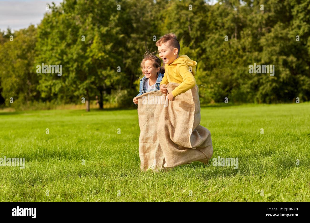happy children playing bag jumping game at park Stock Photo - Alamy