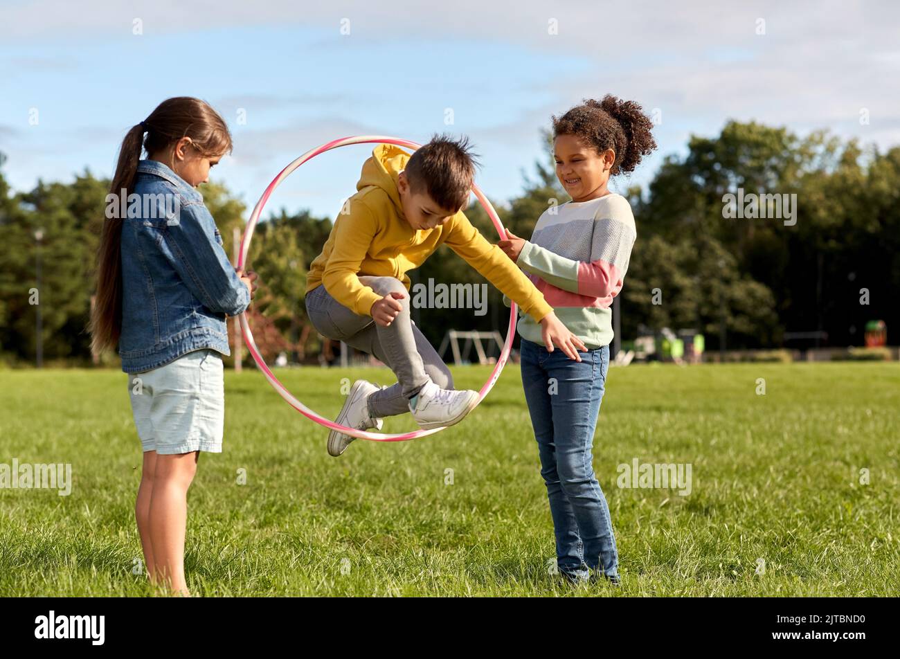 happy children jumping through hula hoop at park Stock Photo - Alamy