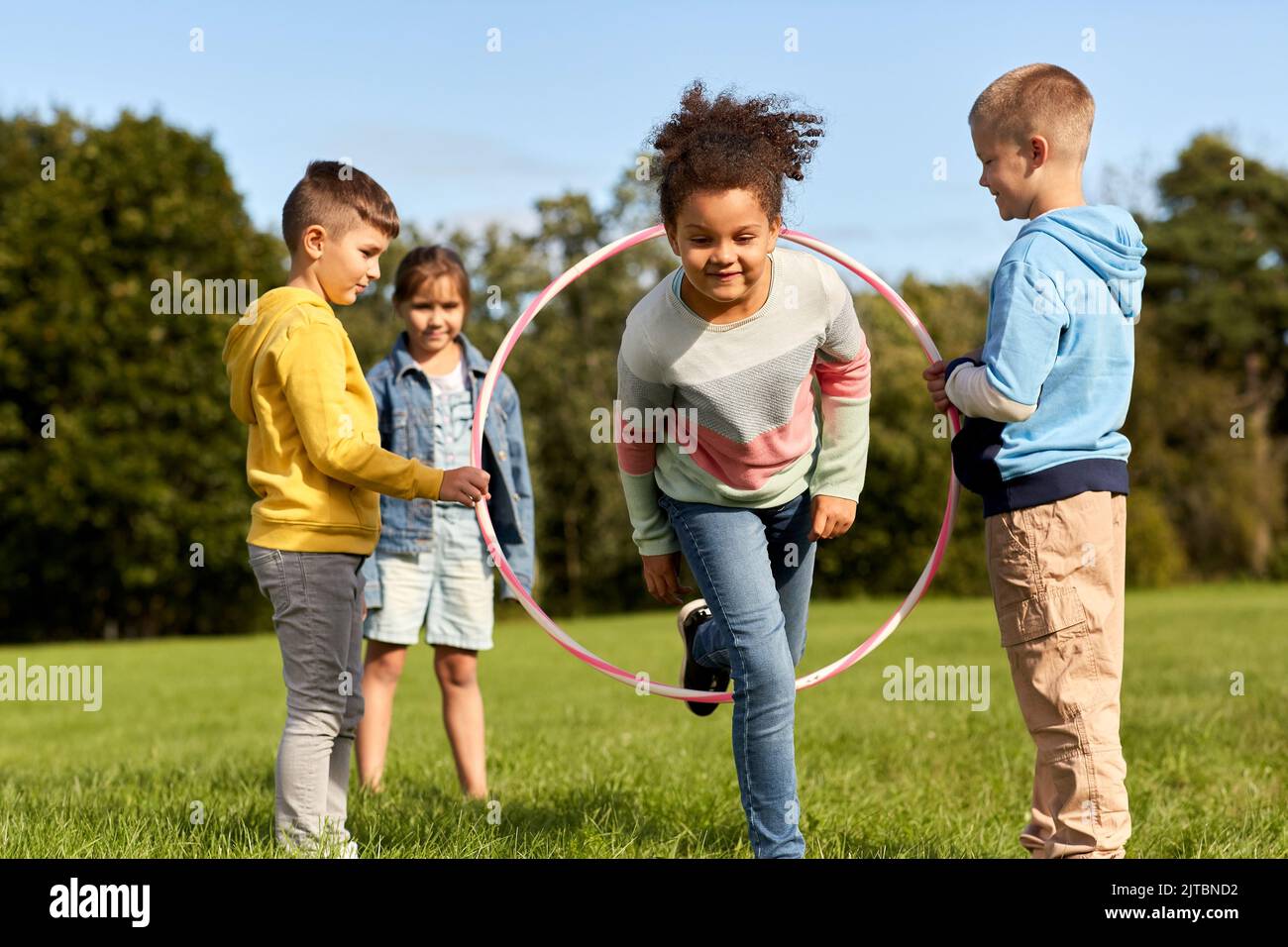 happy children playing game with hula hoop at park Stock Photo - Alamy