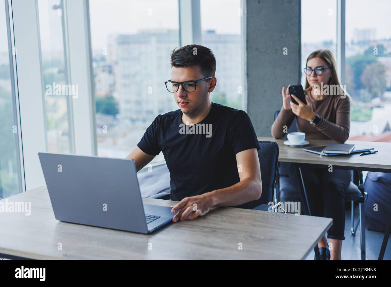 Young colleagues in the office at the desktop with a laptop. Young ...