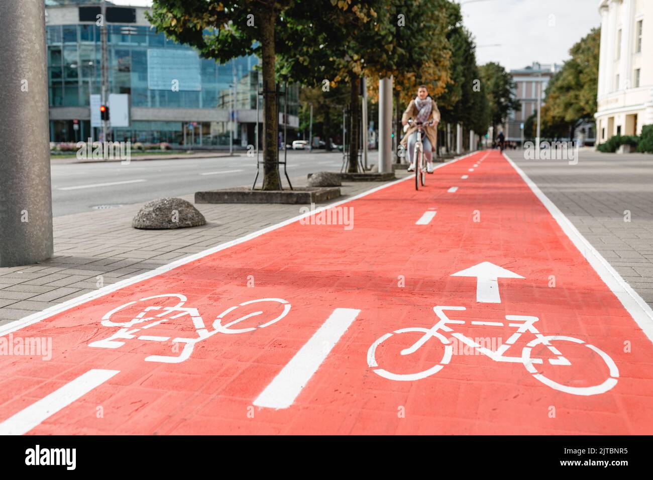 woman cycling along red bike lane road in city Stock Photo - Alamy