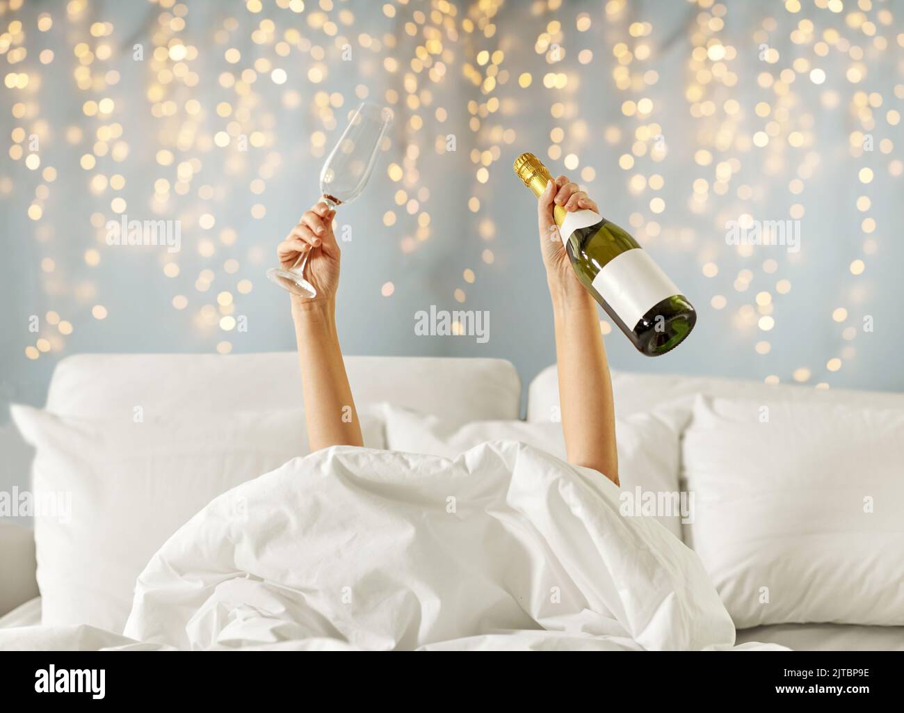 hands of woman lying in bed with champagne Stock Photo - Alamy