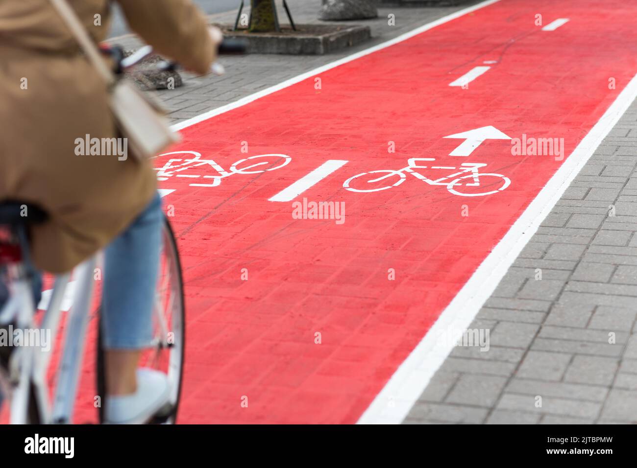 woman cycling along red bike lane road in city Stock Photo - Alamy
