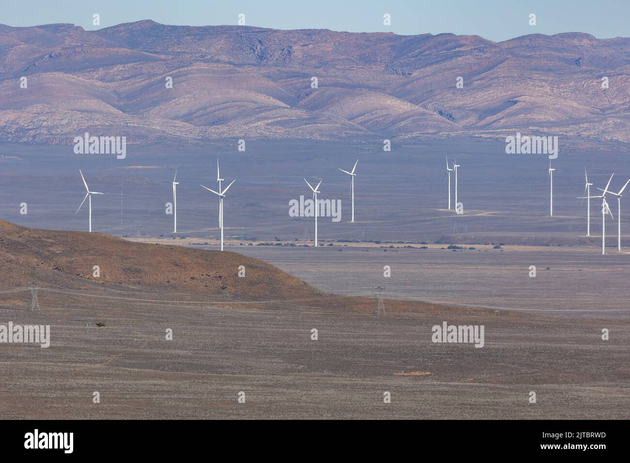 The wind turbines spinning in large field with mountains in the ...