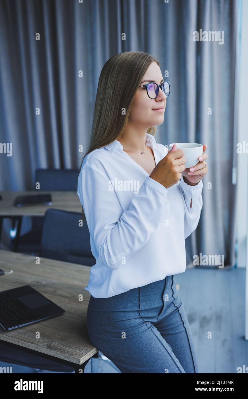 Young Smiling Business Woman Standing In Office Near Window With Coffee