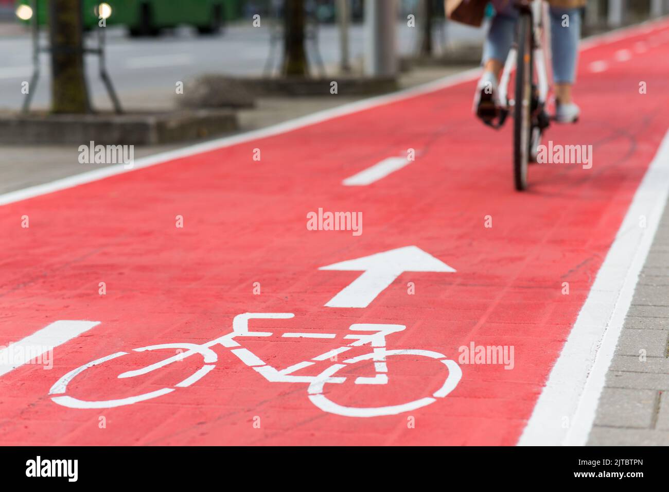 woman cycling along red bike lane road in city Stock Photo - Alamy