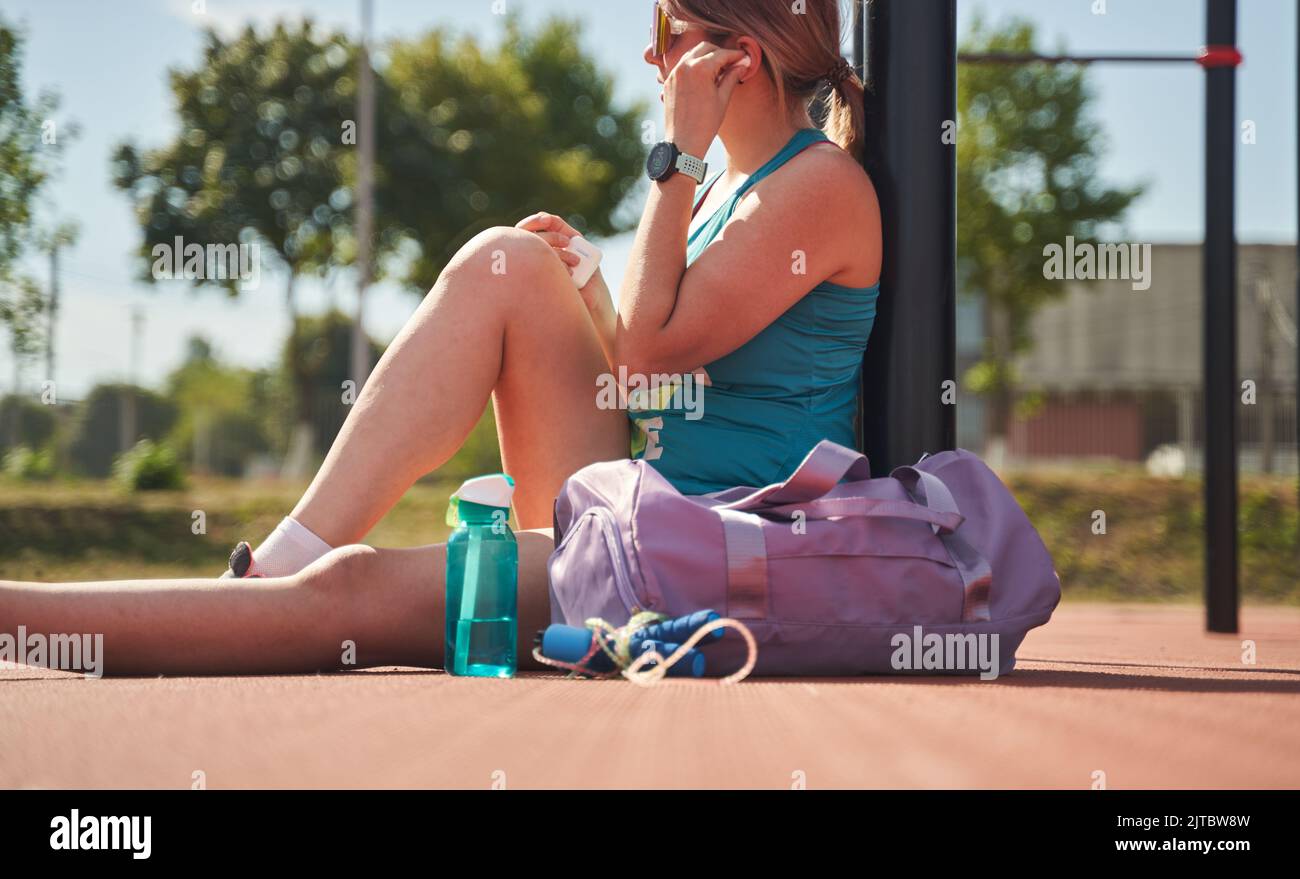 Sport woman relaxing after workout at the stadium, runner taking break ...