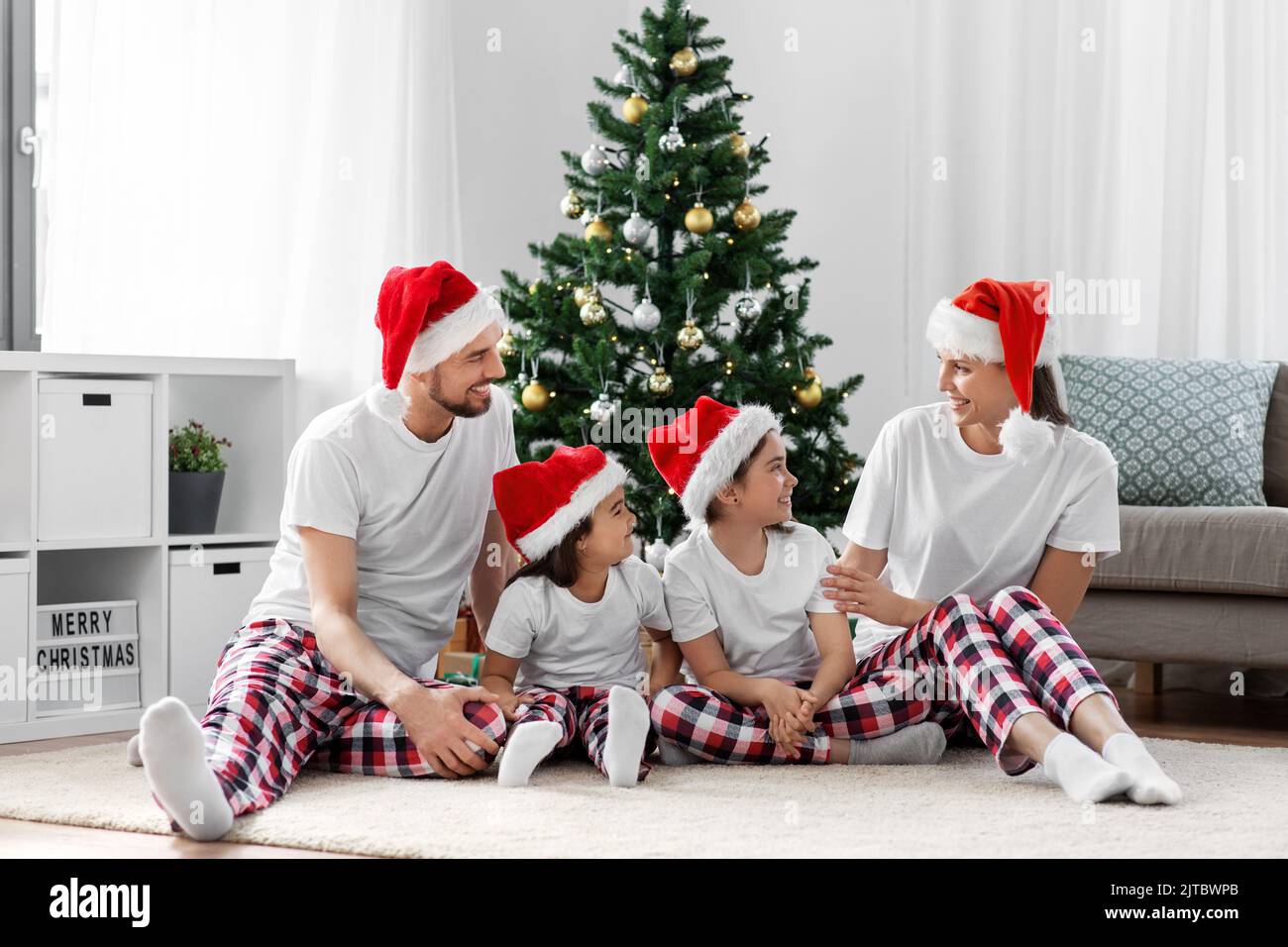 happy family sitting under christmas tree at home Stock Photo - Alamy