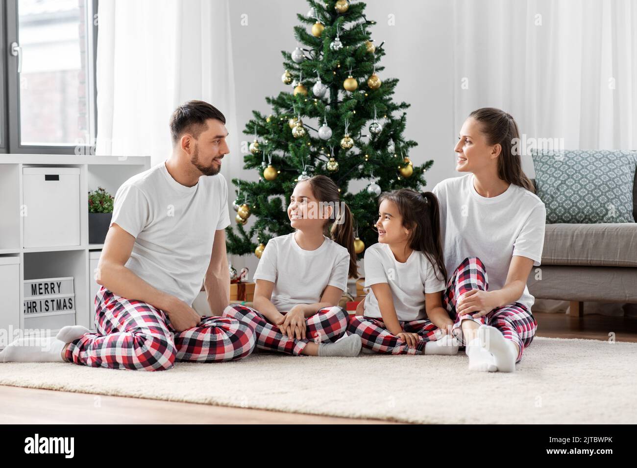 happy family sitting under christmas tree at home Stock Photo - Alamy